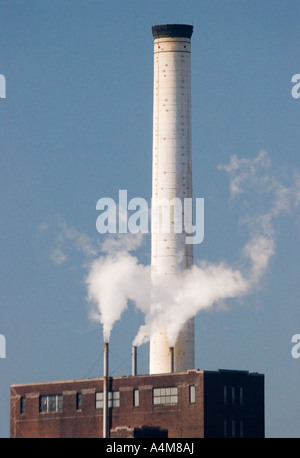 A tall smokestack rises above a brick factory building Stock Photo - Alamy