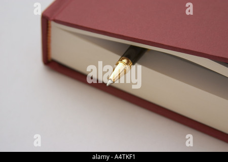 pen wedged between a red book concept knowledge education homework ...