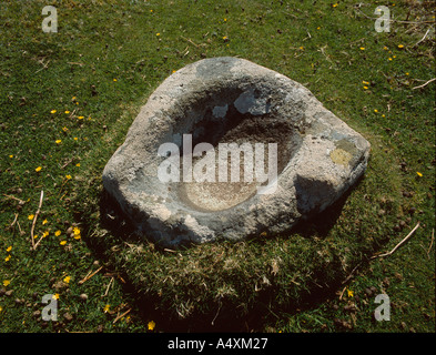 The ancient Quern stone hand mill with grain. The man grinds the grain ...
