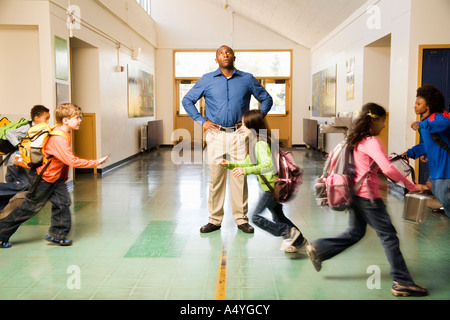 Blurred motion shot of students running past teacher Stock Photo - Alamy