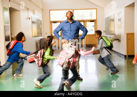 Blurred motion shot of students running past teacher Stock Photo - Alamy