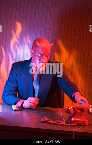 Businessman dressed as devil at desk Stock Photo - Alamy