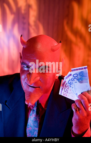 Businessman dressed as devil holding money Stock Photo - Alamy