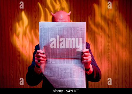Businessman dressed as devil reading newspaper Stock Photo - Alamy