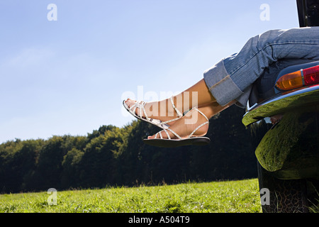 Woman's legs sticking out of a car window by a field of sunflowers in ...