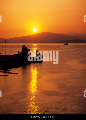 Sun setting over calm sea with gentle waves on sandy beach, wide view ...