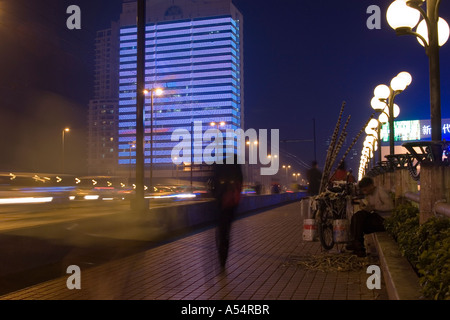 Sugar cane vendor with passing traffic and lit up building on a bridge ...