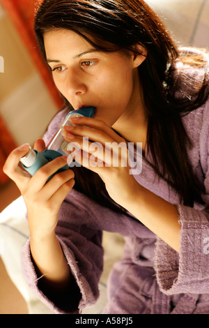 Asthma spacer. Young girl using a spacer (plastic chamber) with an ...