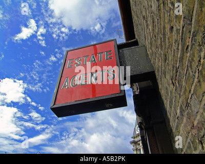 Bright red estate agent's sold sign outside a house in the winter with ...