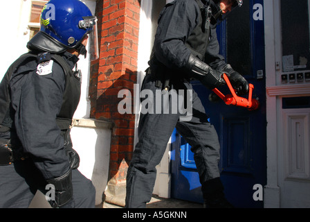 Police break down a front door during a raid on suspected drugs dealers ...