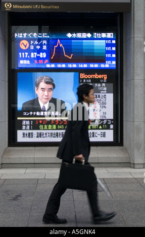 A man walks past a screen showing Japan's Nikkei 225 index at a ...