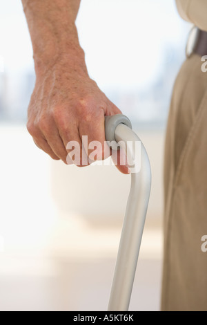 Senior person hand grasping a walking stick, symbolizing support ...