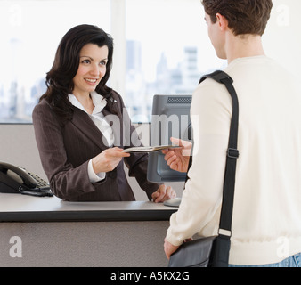 Woman handing paperwork over counter Stock Photo - Alamy