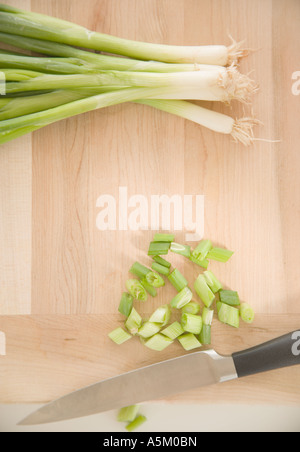 Fresh green onions on a cutting board over white wooden background ...