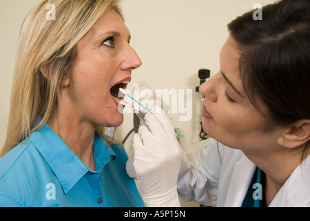 Doctor or nurse swabs the cheek of a female patient to collect buccal ...
