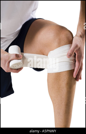 Man wrapping knee in a bandage Stock Photo - Alamy