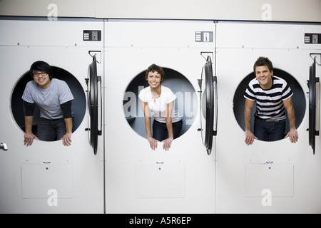 Three people in dryers at Laundromat smiling Stock Photo - Alamy