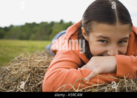 Portrait of a girl leaning over a haystack Stock Photo - Alamy