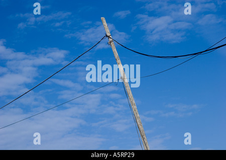 Leaning pole supporting electrical cable and telephone wire Stock Photo ...