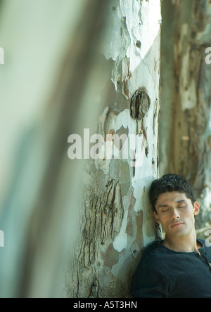 Man casually leaning against a tree Stock Photo - Alamy