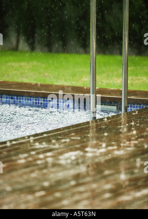 Outdoor swimming pool in the rain; the raindrops hitting the pool water ...