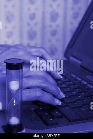 Hourglass measuring time as woman works on laptop computer, symbolizing ...