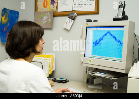 female geologist working at computer with seismic record on screen ...