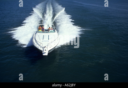Couples running motor boat with wake and excitement as it moves thru ...