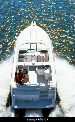 Couples running motor boat with wake and excitement as it moves thru ...
