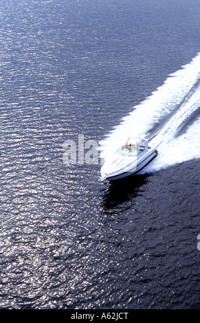Couples running motor boat with wake and excitement as it moves thru ...