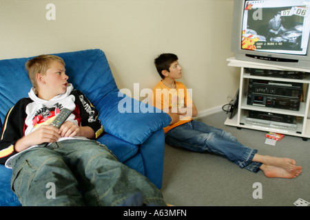 portrait of a young boy glued to the television with his feet on the ...