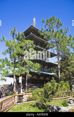 A traditional Japanese pagoda towers in the sky, set against a lush and ...