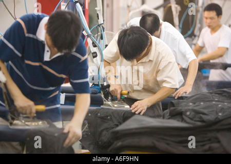 SHENZHEN GUANGDONG PROVINCE CHINA Men ironing finished clothing in a ...