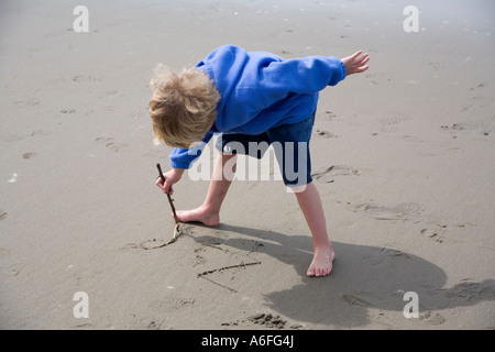 Boy writing in sand with stick, Grand Sand Dunes National Park ...