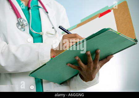 Doctor holding file folder in front of white wall Stock Photo - Alamy