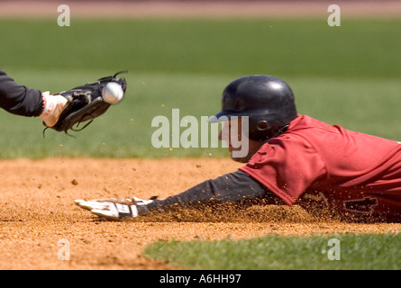 Baseball player head first sliding into third wearing sliding gloves as ...