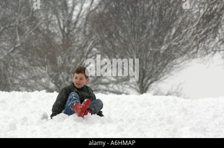 A boy enjoys sledging in the winter snow in England on a tea tray Stock ...