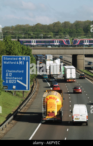 M25 motorway signs & railway bridge with Greater Anglia passenger train ...