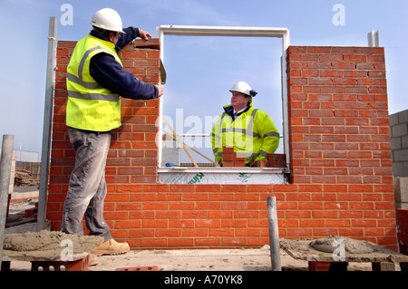Bricklayer hands laying the first course of bricks on house foundation ...