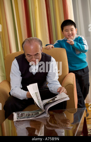 Young boy sneaking up on grandfather Stock Photo - Alamy