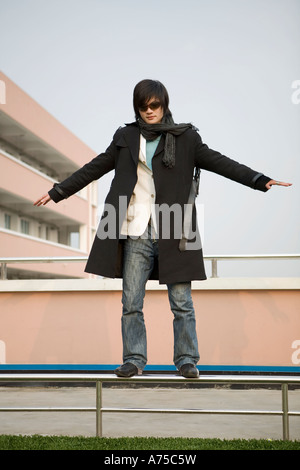 Man standing balancing on metal post looking towards expansive sky ...