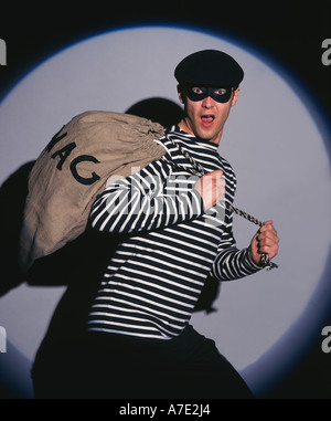 Burglar in traditional costume with swag bag and keyboard stealing a ...