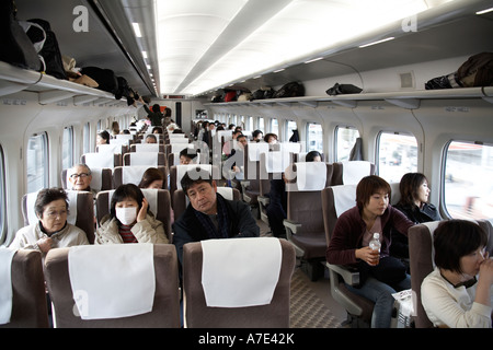Interior of Japanese bullet train Hikari. Passengers seat in half-empty wagon. Shinkansens of ...