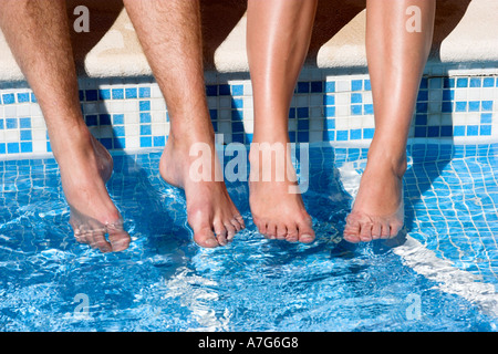 Young woman dipping toe in swimming pool Stock Photo - Alamy