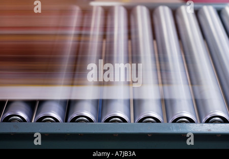 Product moving along steel rollers in factory Stock Photo - Alamy