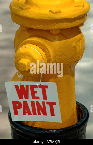 Freshly painted yellow fire hydrant with "Wet Paint" sign stuck on ...