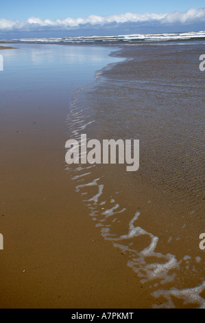 A wide gently sloping beach with small waves lapping washing in Morgan ...