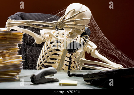 Skeleton sitting at desk with stacks of paperwork and crumpled papers ...