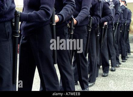 A line of police officers hold batons while forming a nighttime line in ...