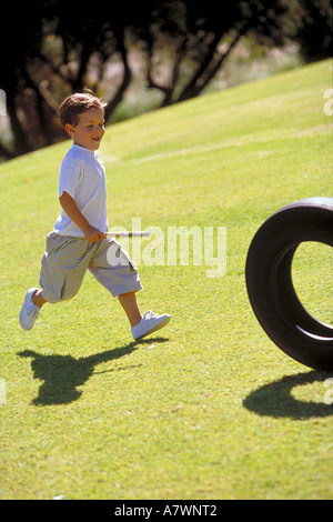 running boy rolling a tyre across the meadow Stock Photo - Alamy
